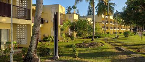 Um hotel com vários andares, área de estar externa e palmeiras.