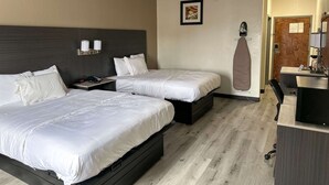 Quarto de hotel com duas camas, uma escrivaninha, uma cadeira, um guarda-roupa e um espelho.