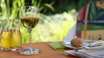 Uma mesa com um copo de vinho branco, um jarro, um prato com um pastel e um garfo.