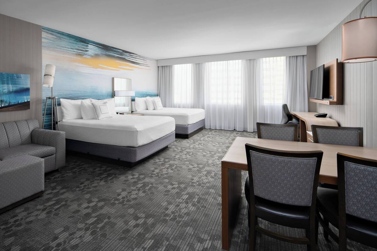 Quarto de hotel com uma cama grande, um sofá, uma mesa e uma televisão.