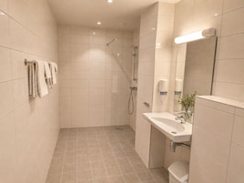 Quarto Twin Standard, adaptado para pessoas com dificuldades de mobilidade | Casa de banho | Um polibã, toalhas fornecidas, sabão, champô