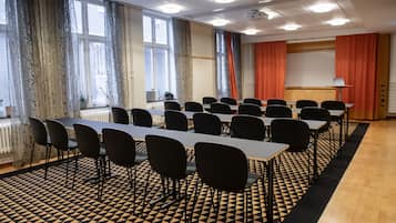 Sala de conferência com uma mesa comprida, cadeiras, projetor e cortinas.