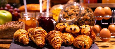 Uma mesa farta com croissants, pão, ovos e frutas.