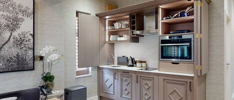 Cozinha moderna com eletrodomésticos embutidos, área de jantar com mesa e cadeiras, e uma planta decorativa.