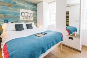 Quarto moderno com uma cama grande, um cobertor azul e uma obra de arte na parede.