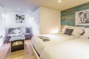 Um quarto moderno com uma cama, um sofá e uma mesinha de cabeceira com abajur.