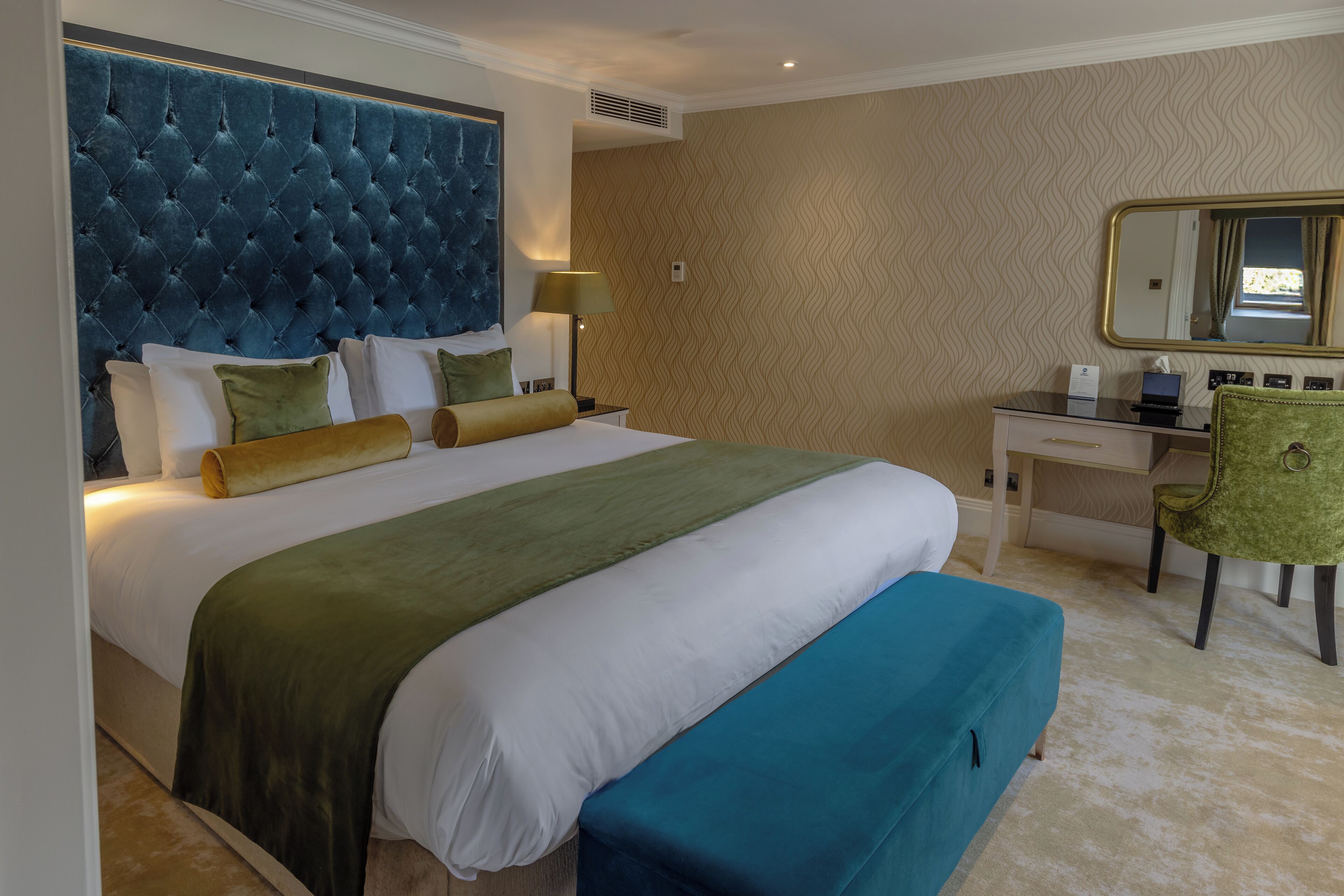 Quarto de hotel com uma cama grande, uma escrivaninha e uma cadeira.