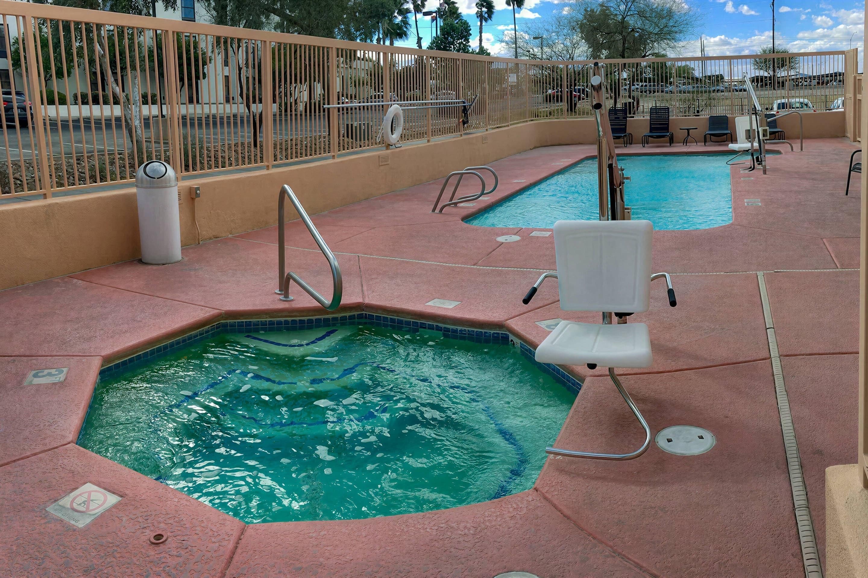 Área da piscina com hidromassagem, espreguiçadeiras e uma cerca.
