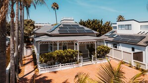 Uma casa residencial com varanda coberta, painéis solares no telhado e um caminho de tijolos.