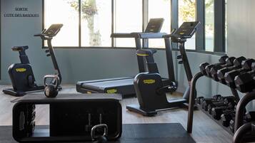 Uma academia com esteiras, um kettlebell e halteres.