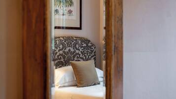 Quarto com uma cama, cabeceira estampada e ilustração botânica emoldurada na parede.