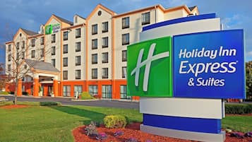 Um hotel Holiday Inn Express & Suites com uma grande placa, vários andares e um gramado bem cuidado.