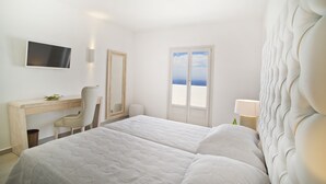 Quarto com cama, escrivaninha, cadeira, televisão e janela com vista.