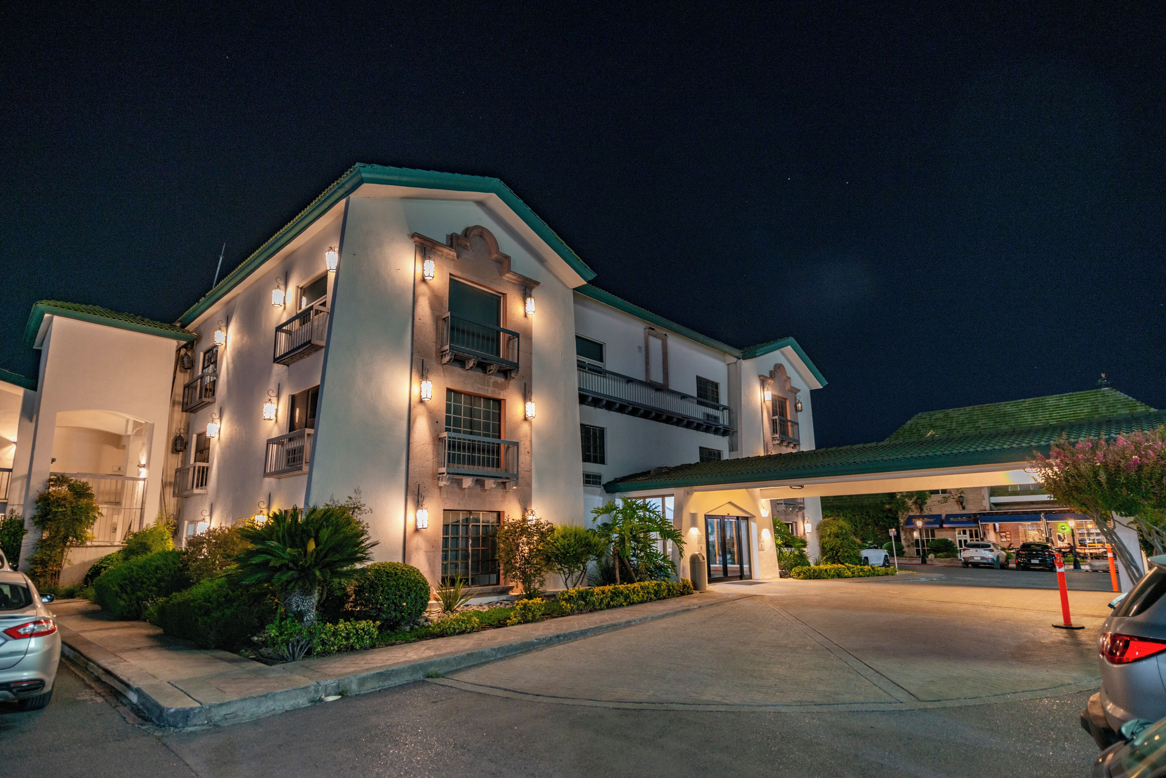 Um hotel com vários andares, entrada bem iluminada e área de estacionamento coberta.