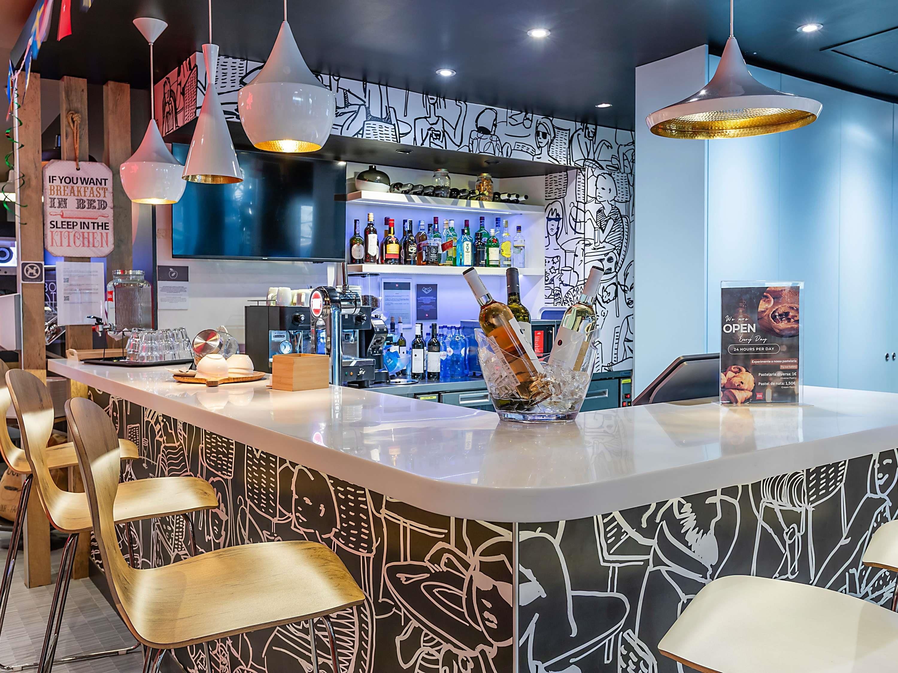 Uma área de bar com balcão, banquetas e diversos tipos de garrafas.