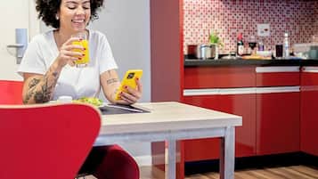 Cozinha moderna com armários vermelhos, micro-ondas e área de jantar com mesa e cadeiras.