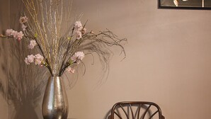 Um quarto com uma mesa redonda, um vaso com flores e uma cadeira.