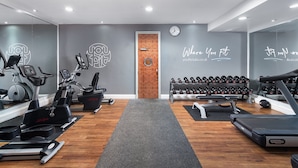 Uma academia com equipamentos de cardio, halteres e esteira.