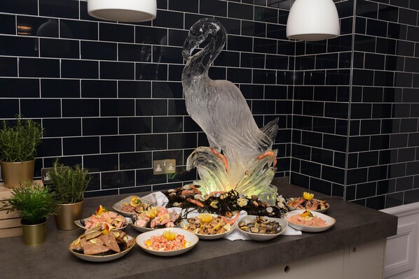 Uma bancada de cozinha com diversos pratos de frutos do mar e uma escultura de vidro decorativa.