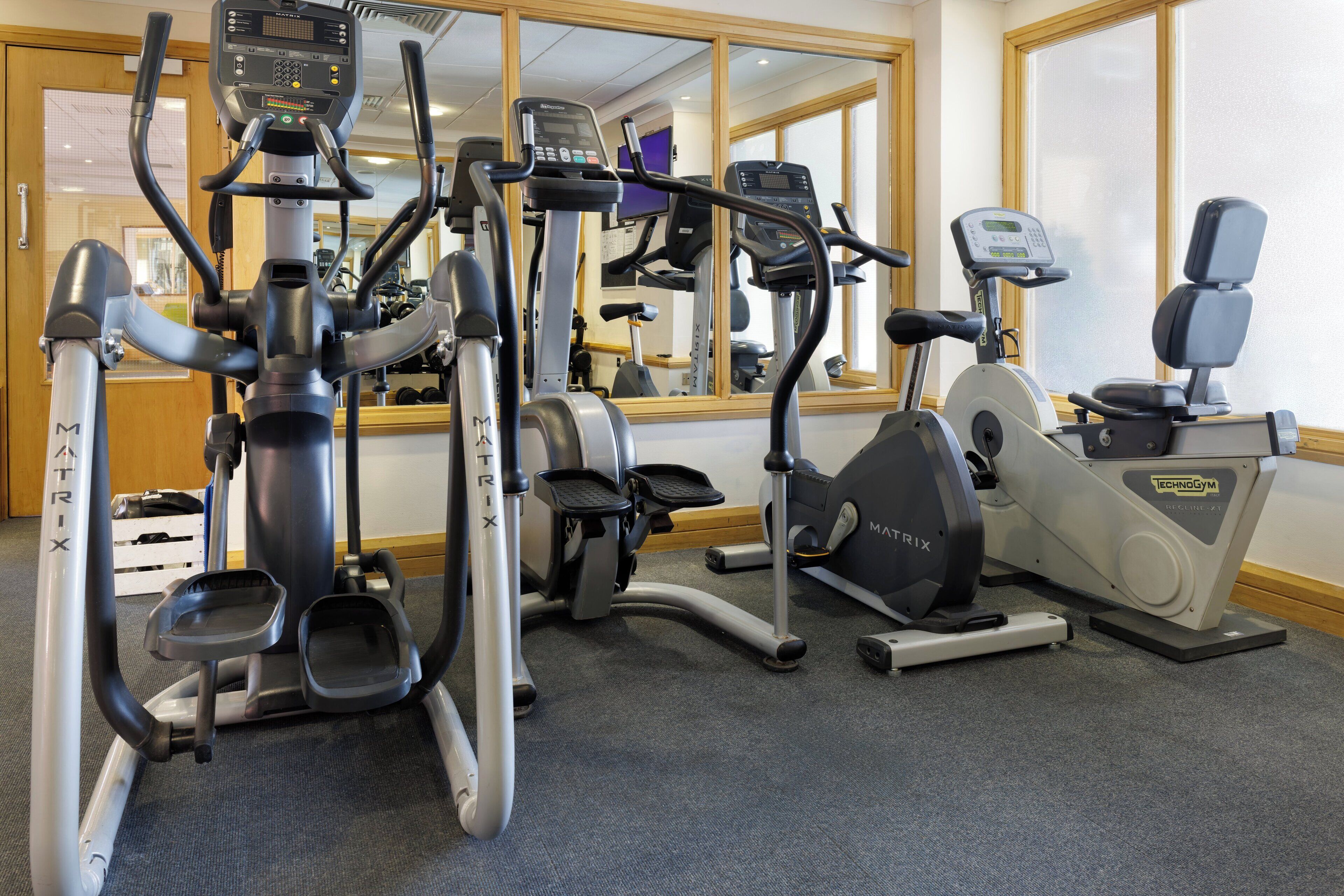Uma academia com diversos equipamentos de cardio, incluindo esteiras e elípticos.