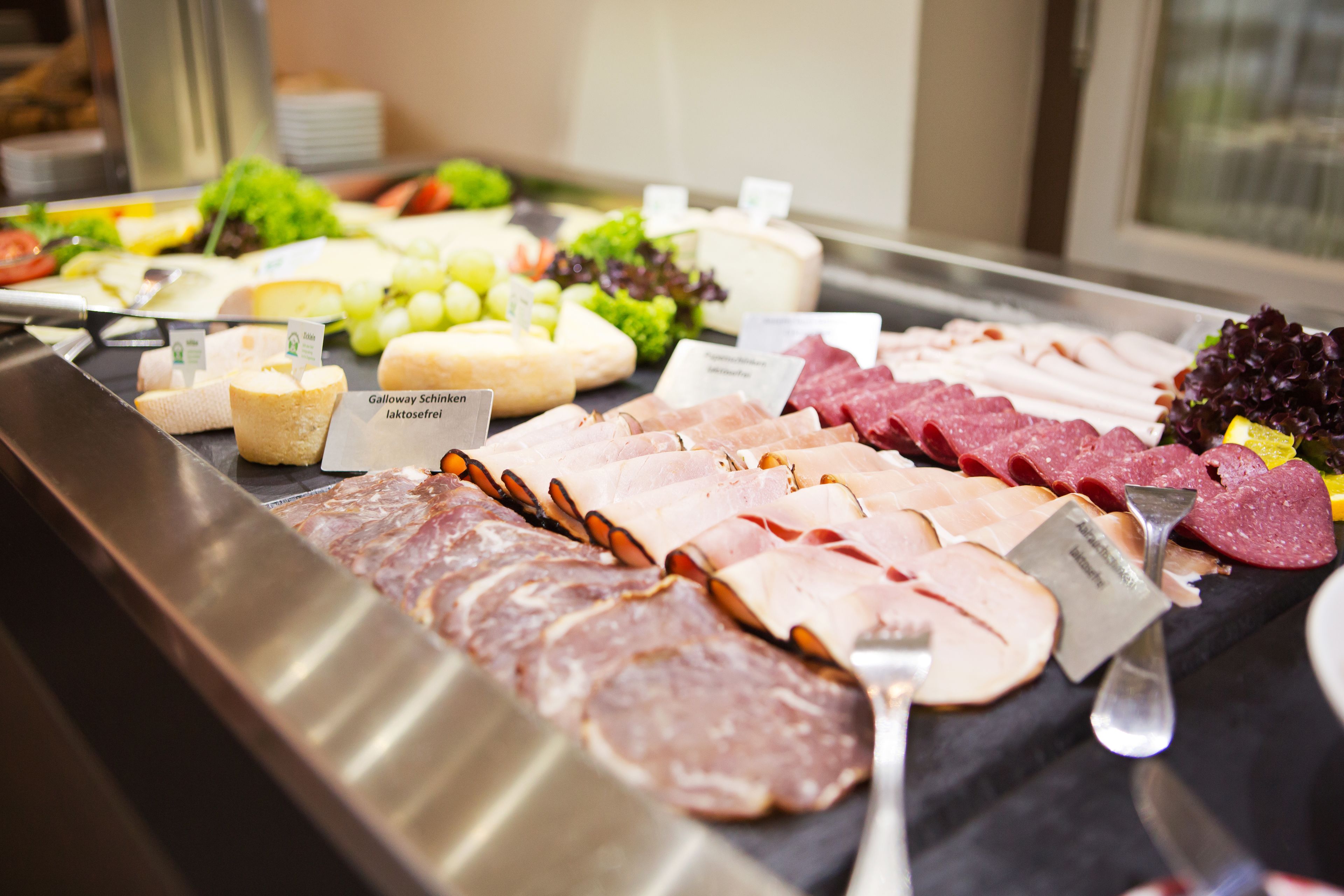 Um buffet com diversos carnes, queijos e frutas.