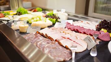 Um buffet com diversos carnes, queijos e frutas.