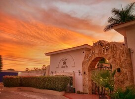 Entrada de hotel com arco de pedra com a inscrição "SANTA FE HOTEL" e uma placa acima.