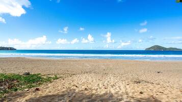 Uma praia com céu azul límpido e ondas do oceano.
