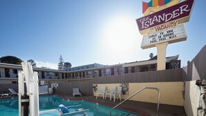 Um motel com piscina, placa indicando quartos disponíveis e comodidades como TV a cabo, HBO, ar condicionado nos quartos e Wi-Fi gratuito.
