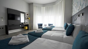 Quarto de hotel com duas camas, televisão, escrivaninha e uma cadeira.