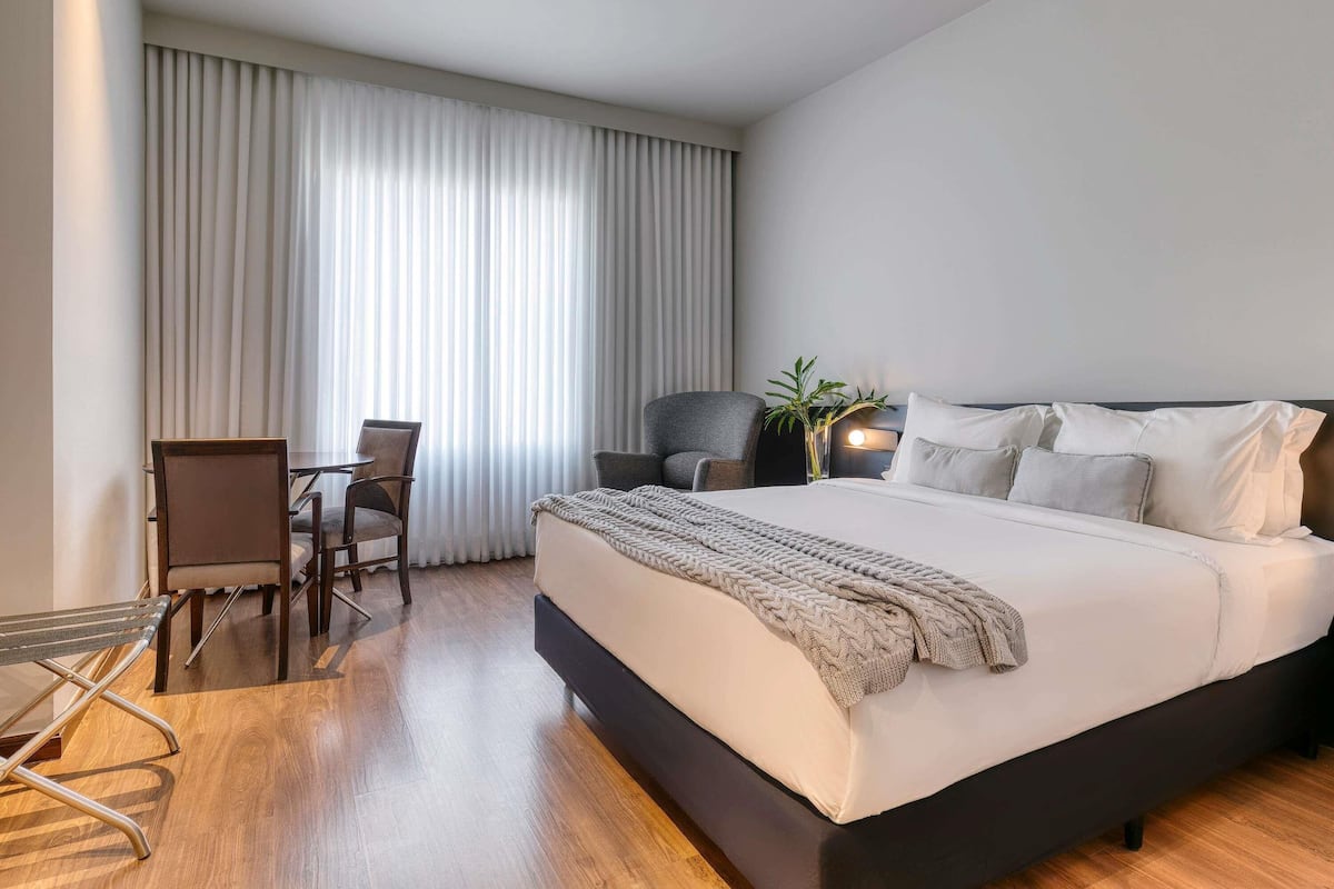 Quarto de hotel moderno com uma cama grande, uma escrivaninha e uma cadeira.