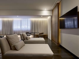 Uma sala de estar moderna com um sofá, uma mesinha e uma TV fixada na parede.