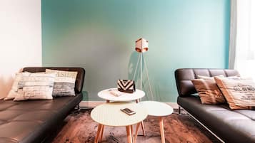 Uma sala de estar moderna com dois sofás de couro preto, uma mesa de centro redonda e um abajur.