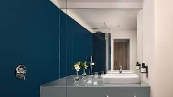 Uma casa de banho moderna com um espelho grande, uma sanita branca e uma parede com detalhes em azul.