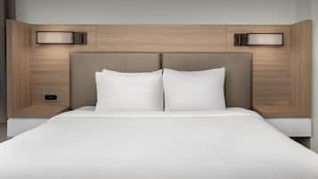 Quarto moderno com uma cama grande, cabeceira de madeira e duas luminárias fixadas na parede.