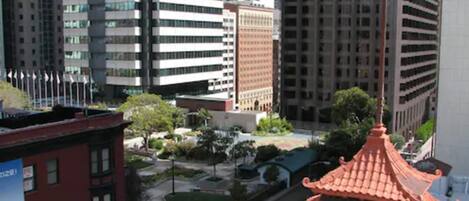 Paisagem urbana com edifícios modernos altos, uma pagoda tradicional e uma pequena área de parque.