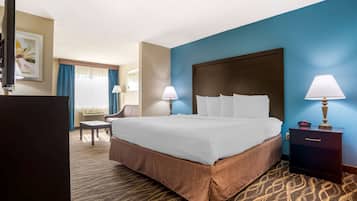 Quarto de hotel com uma cama grande, duas luminárias de cabeceira, uma escrivaninha, uma cadeira e uma televisão.