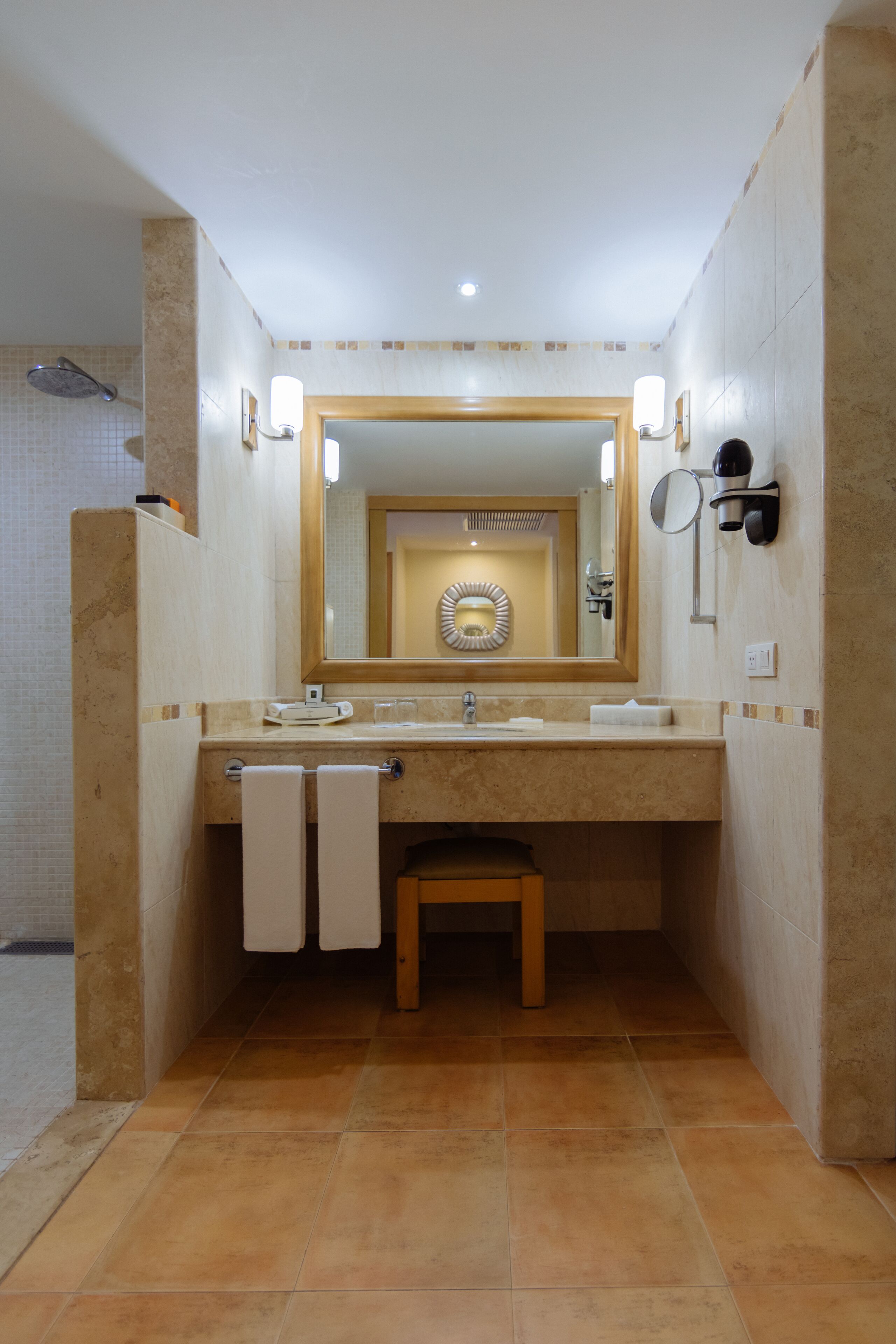 Casa de banho com lavatório, espelho, porta-toalhas e chuveiro.