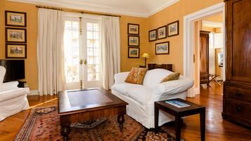 Sala de estar com sofá branco, mesa de centro, tapete estampado e móveis de madeira.