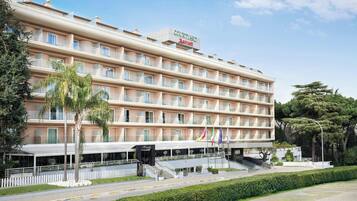Um hotel de vários andares com fachada plana, varandas e uma área de entrada coberta.