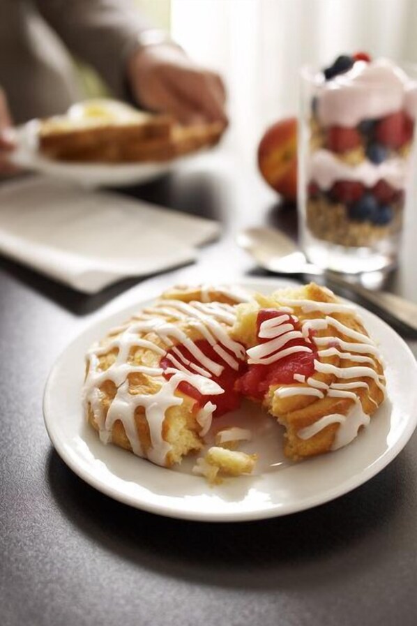 Uma sobremesa em um prato com cobertura branca e pedaços de fruta.