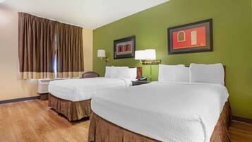 Quarto de hotel com duas camas, paredes verdes e uma janela grande com cortinas.