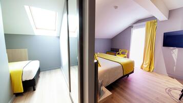 Quarto com uma cama, escrivaninha, cadeira, televisão e janela.