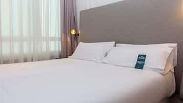 Uma cama bem arrumada com lençóis brancos, cabeceira e abajur.