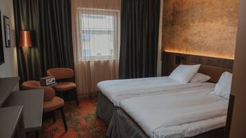 Quarto de hotel com cama, escrivaninha, cadeira e abajur.