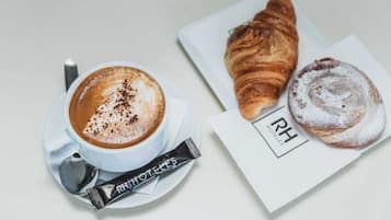 Uma chávena de café com uma colher e um pastel num guardanapo.