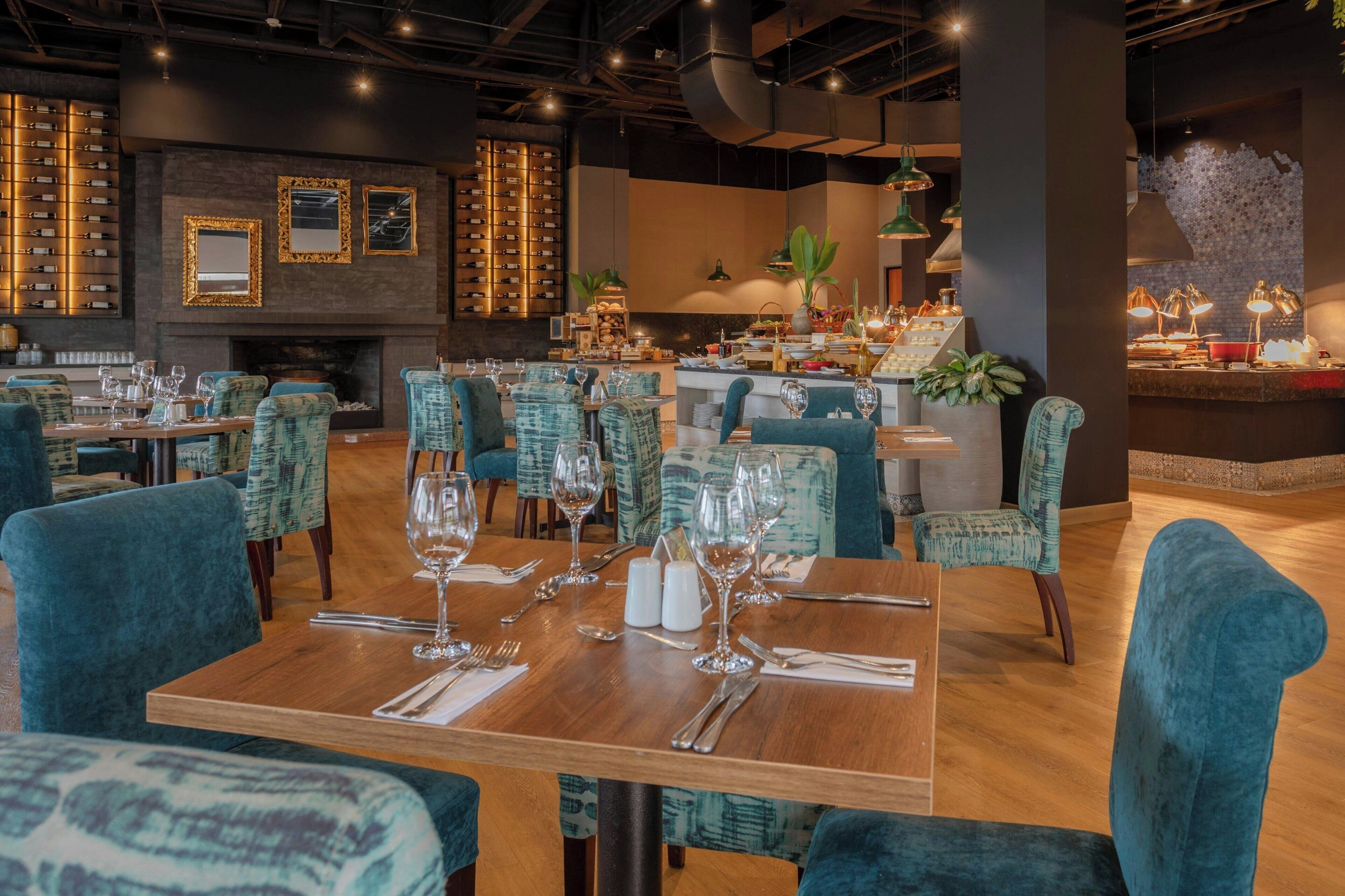 Interior de restaurante com várias mesas de jantar, copos e cadeiras.