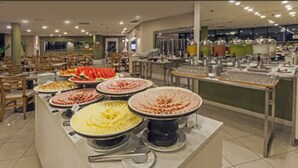 Uma área de buffet com diversos pontos de comida, incluindo um bar de saladas e uma seção de carnes.