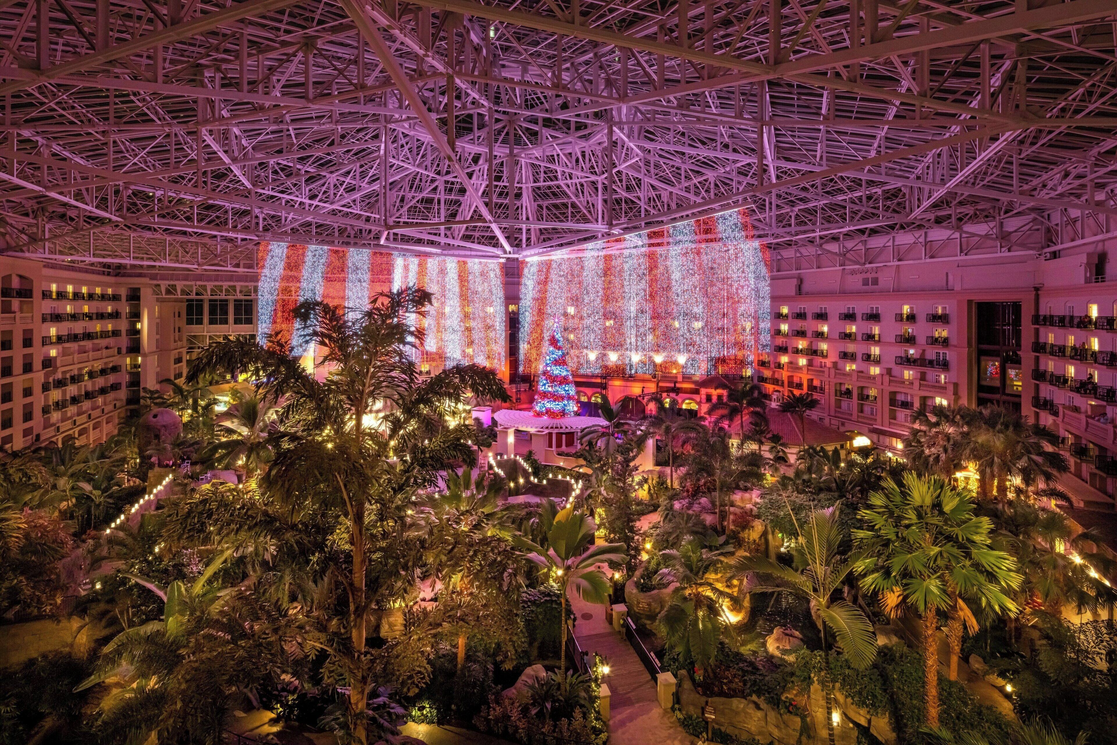 Um átrio de hotel com teto alto, jardim interno e árvore de Natal.