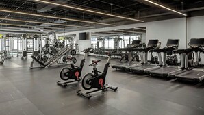 Uma academia moderna com diversos equipamentos de exercício, incluindo esteiras e bicicletas ergométricas, dispostos em um espaço amplo.